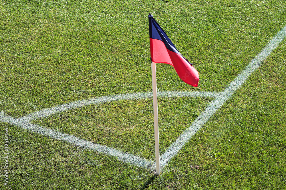 A red and blue flag at one corner of football stadium and soccer corner ...