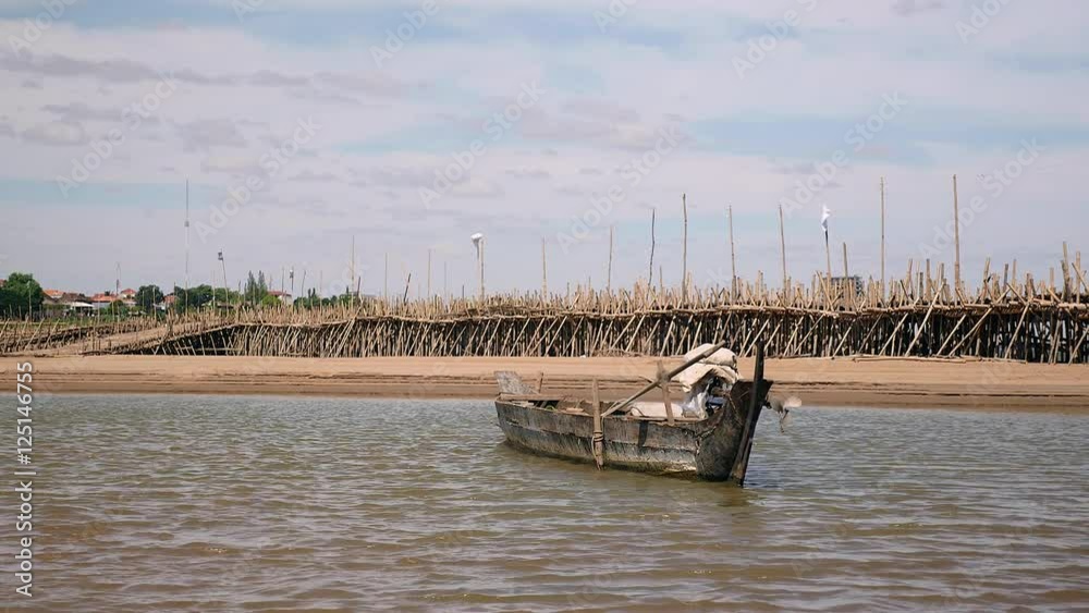Traditional dugout canoes tied up to bamboo poles stuck into the ...