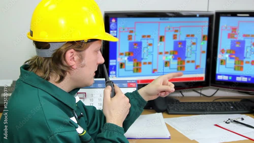Industrial worker in a control room, controls the operation of devices ...