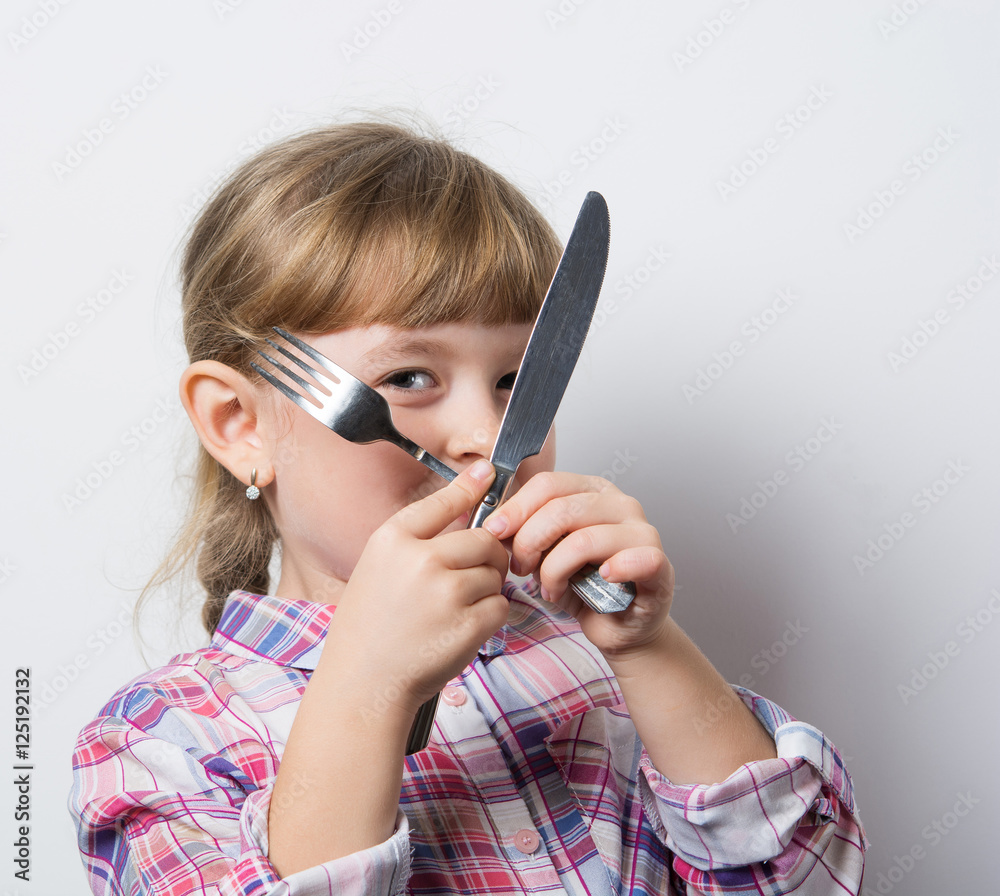 little girl with a knife and fork Photos | Adobe Stock