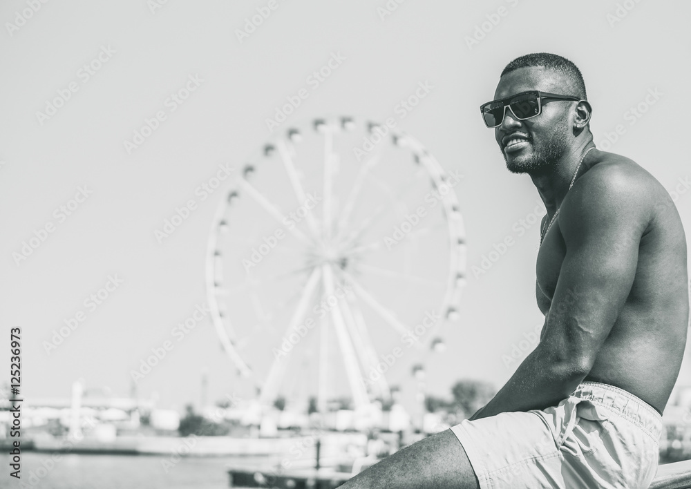 Young muscular black man sitting inside sailing boat with wonder wheel ...