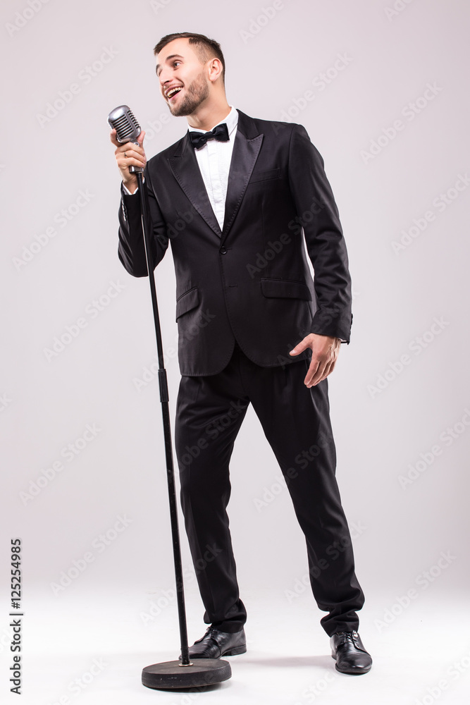 Young man in suit singing over the microphone with energy. Isolated on ...