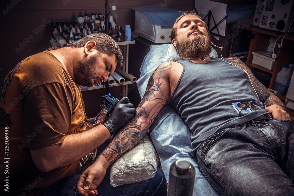 Tattooer showing process of making a tattoo in tattoo studio Stock ...