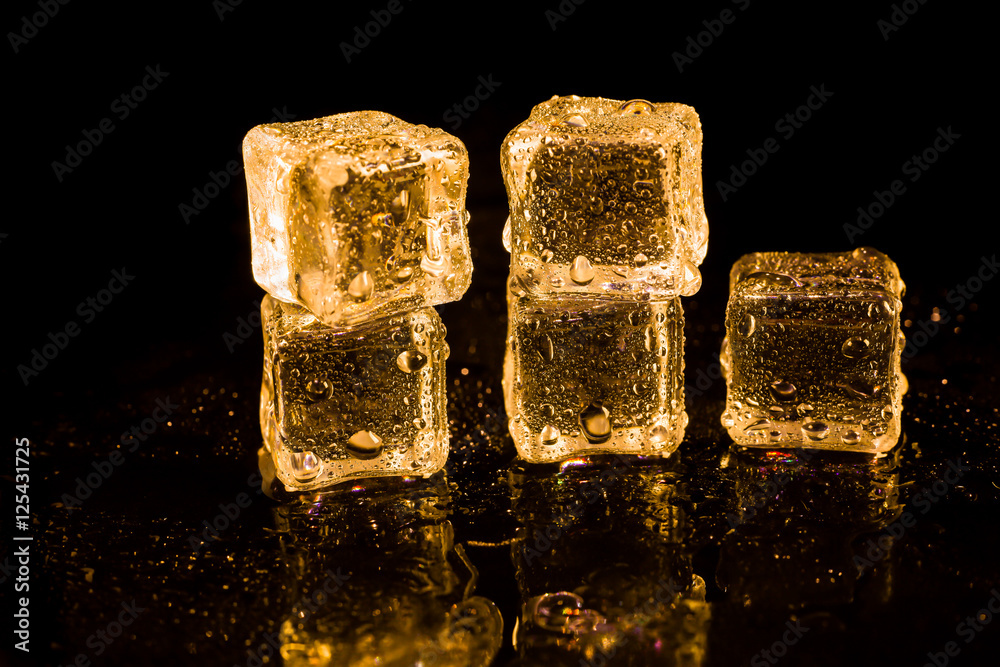 Ice cubes of gold color on a reflective surface. Stock Photo | Adobe Stock