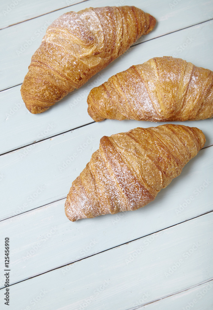 Freshly baked croissant pastries on a wooden kitchen counter background ...