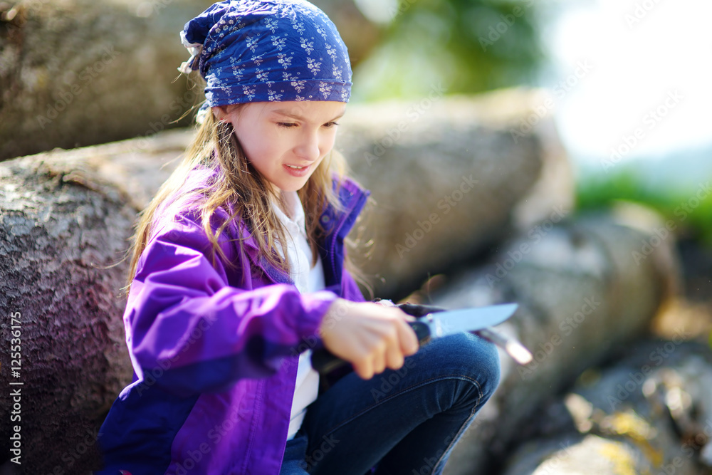 Foto de Cute little girl using a pocket knife to whittle a stick for a ...