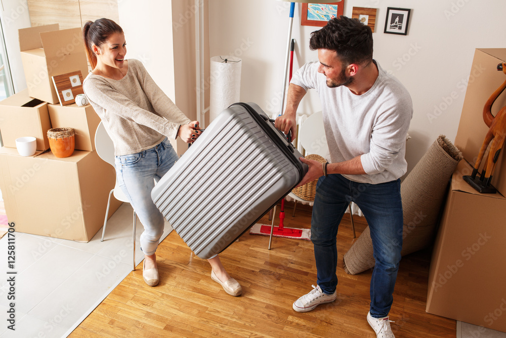 Young married couple moving into new home. They're unpacking card boxes ...