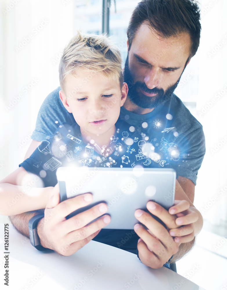 Bearded father with his young son using tablet PC in sunny room.Dad and ...