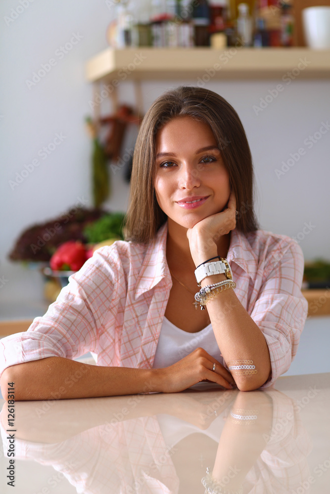 Young woman sitting a table in the kitchen Stock-Foto | Adobe Stock