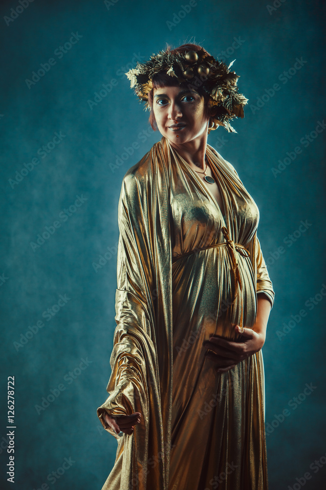 Pregnant woman in golden toga and wreath posing like a Greece fertility ...