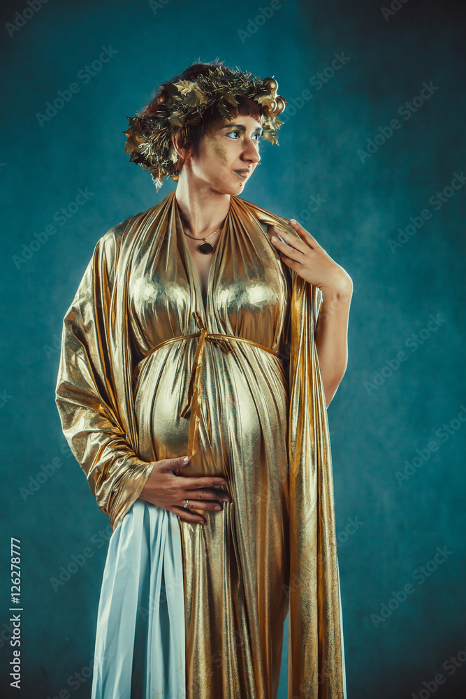 Pregnant woman in golden toga and wreath posing like a Greece fertility ...