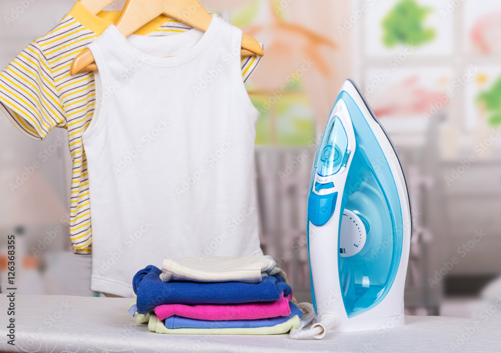 Steam iron, ironing board and clothes children in background room ...