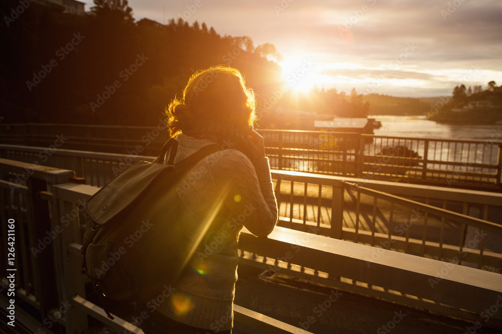 Sad girl looks at the sunset. A girl holding a backpack. Thoughtful ...