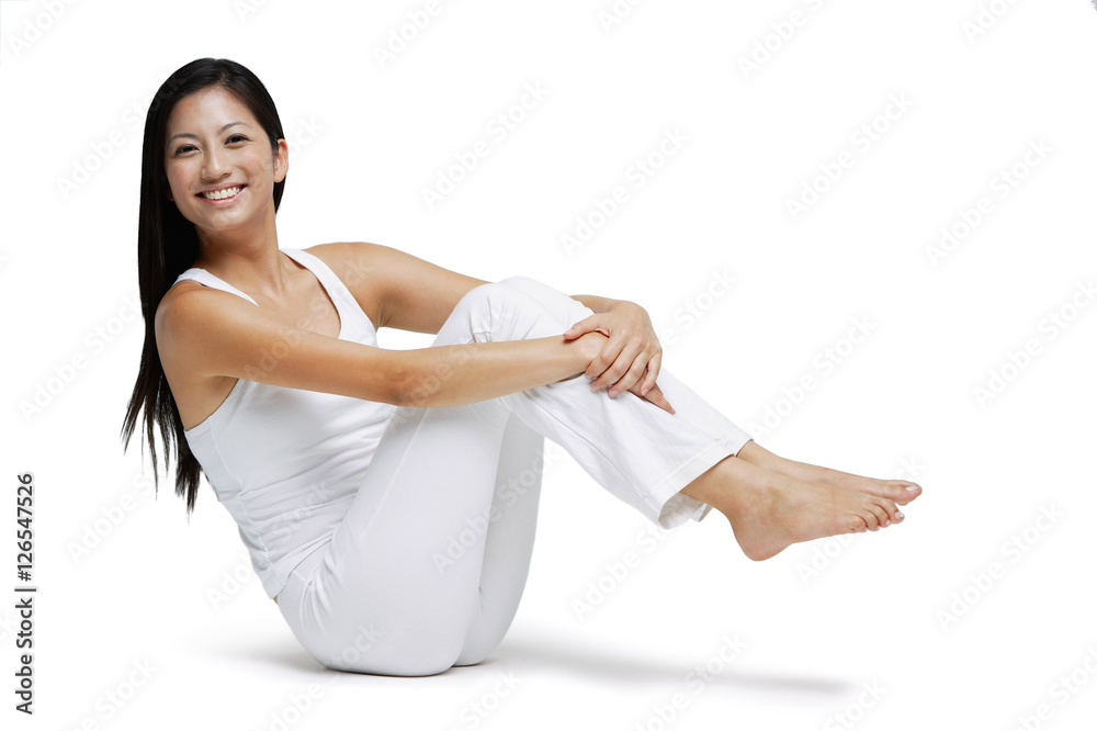 Woman sitting on floor, hugging knees, and lifting legs of floor ...