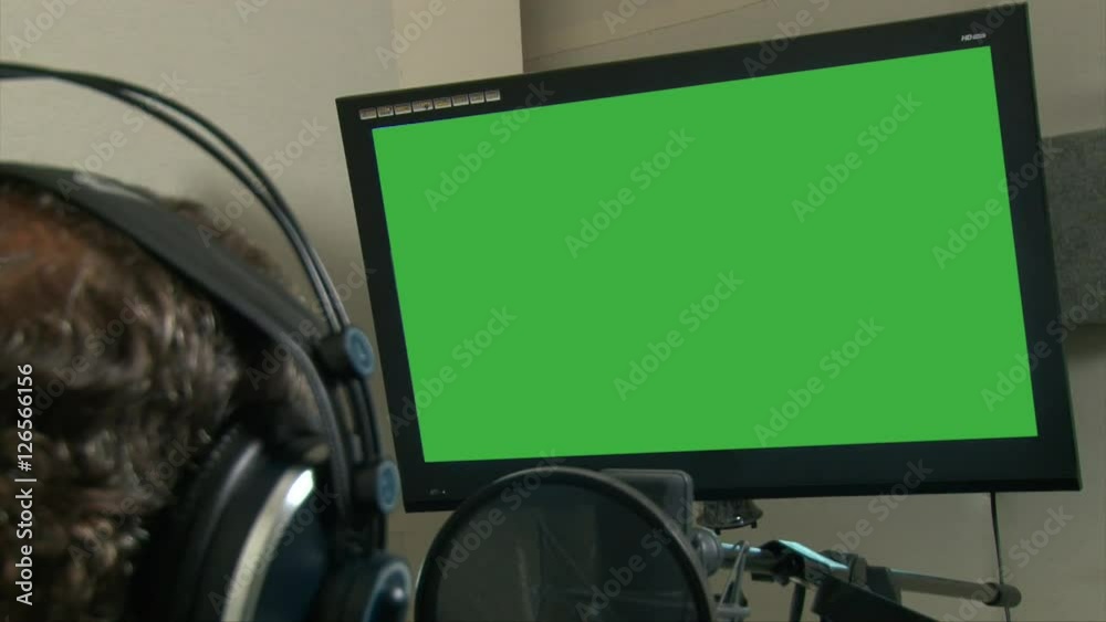 Man sitting back to camera reading text from a green screen in studio ...