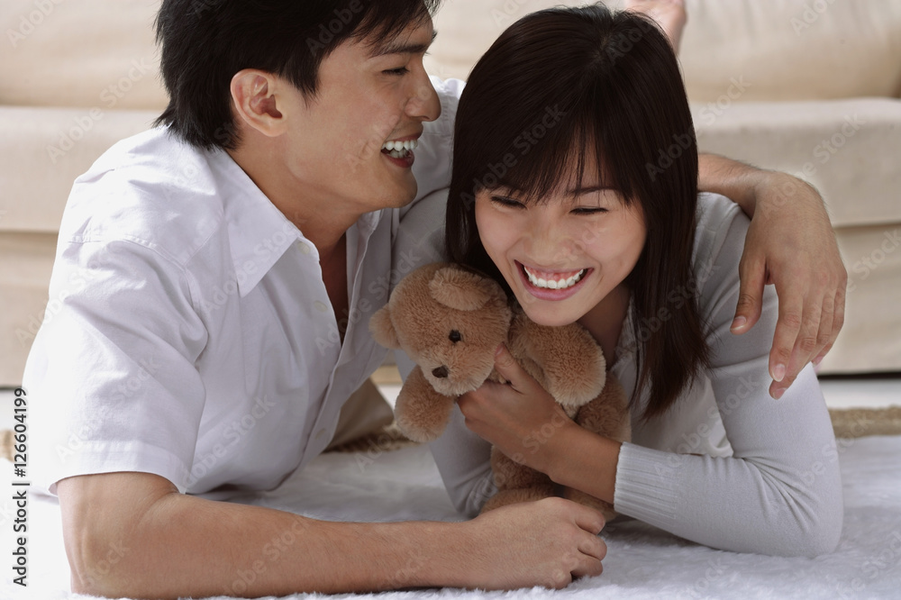 Young couple laughing while hugging and lying on the floor Stock Photo ...