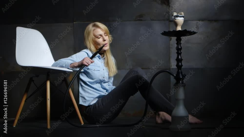 Beautiful young woman inhaling hookah. girl smoking shisha in cafe ...