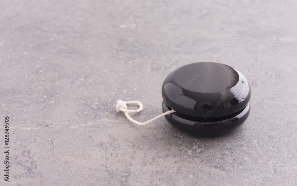 Black wooden yoyo on stone table with copy space. Close up of vintage ...