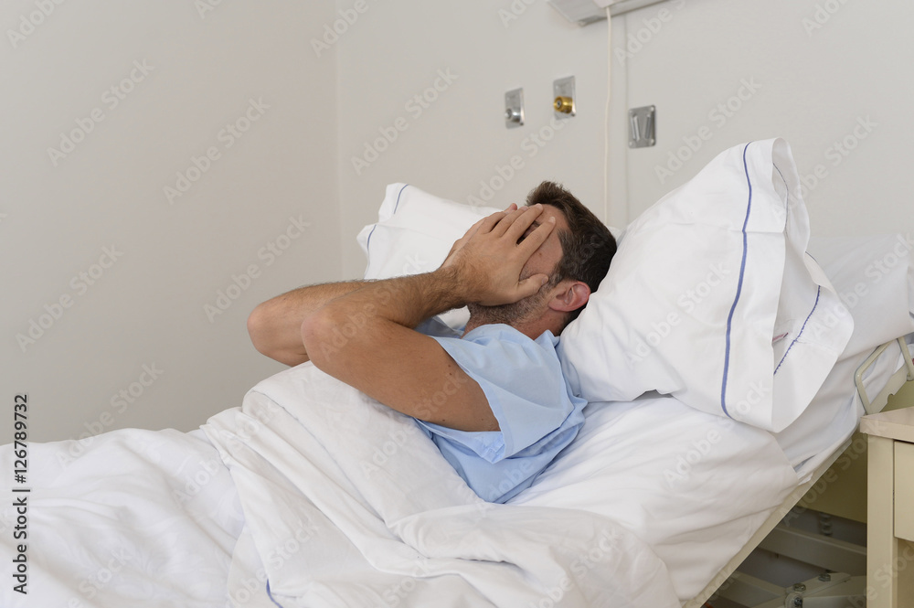 young patient man lying at hospital bed resting tired looking sad and ...