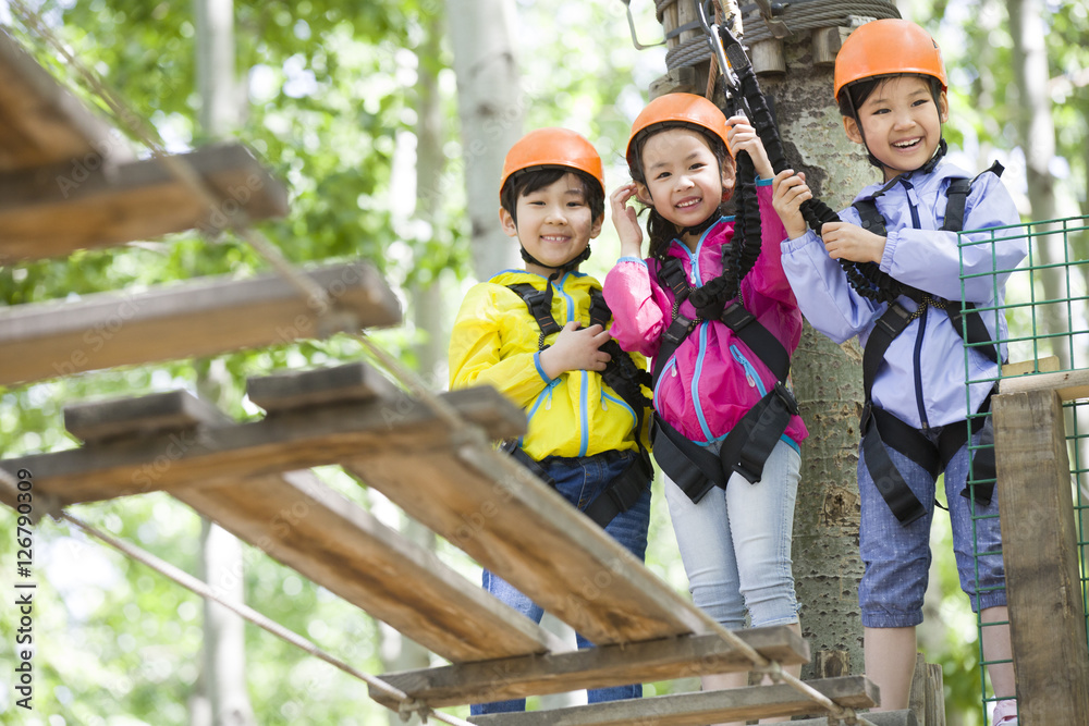 Happy children playing in tree top adventure park Stock Photo | Adobe Stock