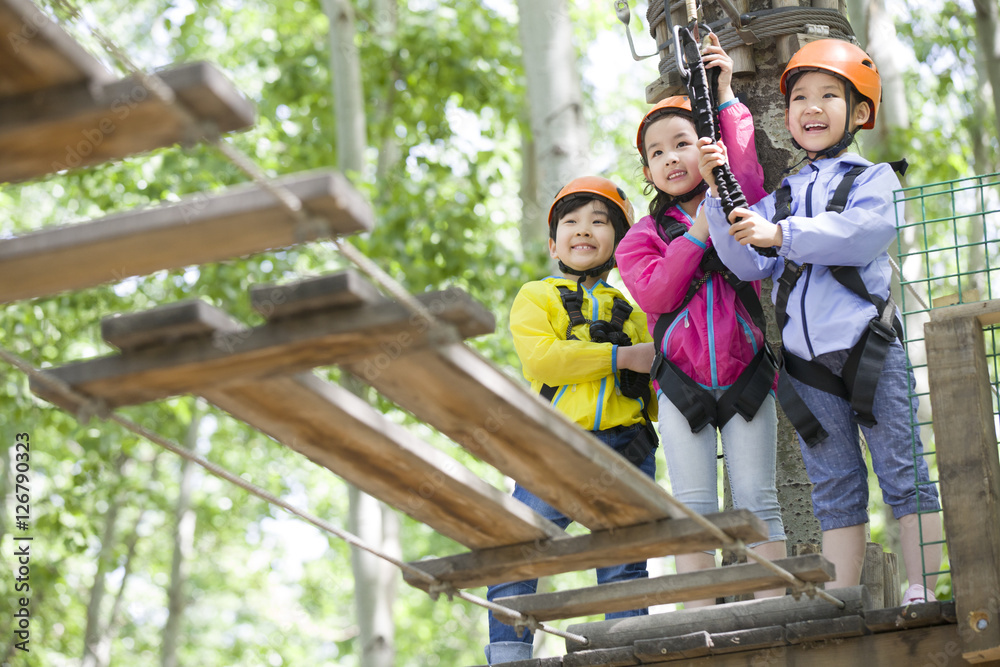 Happy children playing in tree top adventure park Stock Photo | Adobe Stock