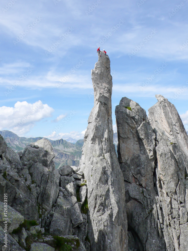 rock climbers on top of a very exposed rock needle in the Swiss Alps ...