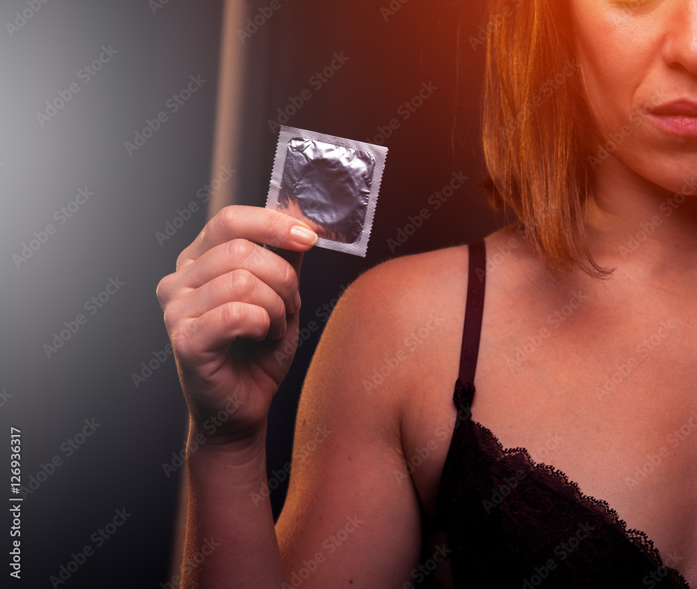 Young sexy woman in lingerie holding condom Stock Photo | Adobe Stock