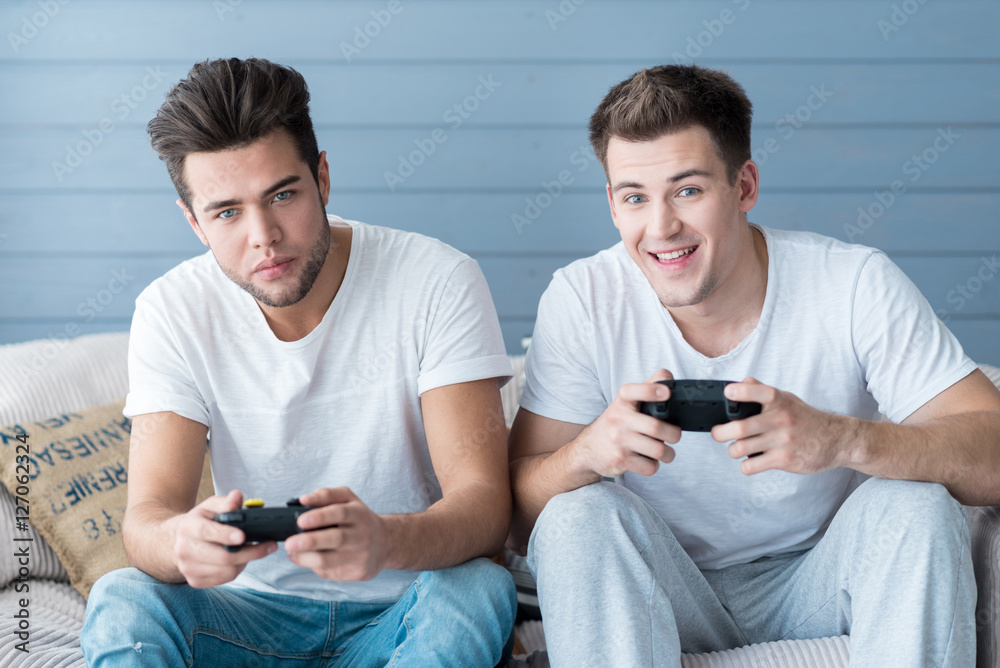 Foto Stock Handsome gay men playing console games together. | Adobe Stock