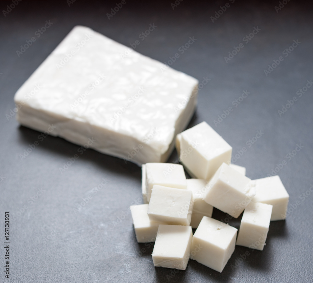 Buffalo paneer Indian cheese on black slate cutting chopping board ...