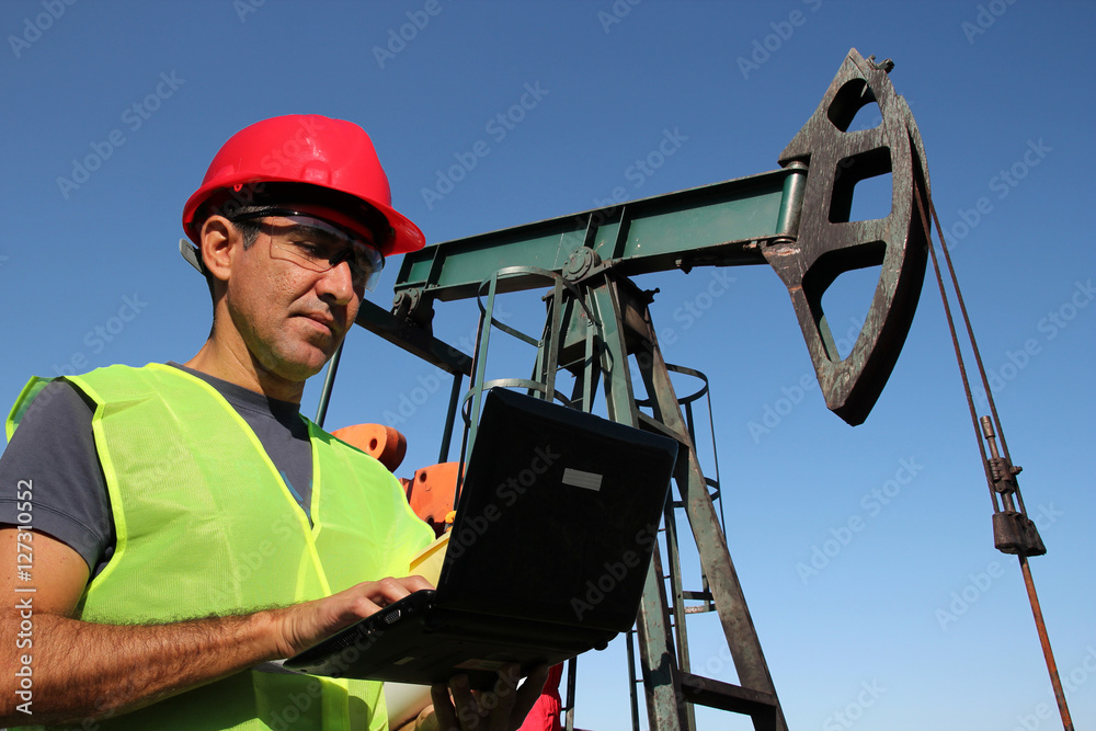 Engineer With Laptop Next to Pump Jack in the Oil Field / Engineer with ...
