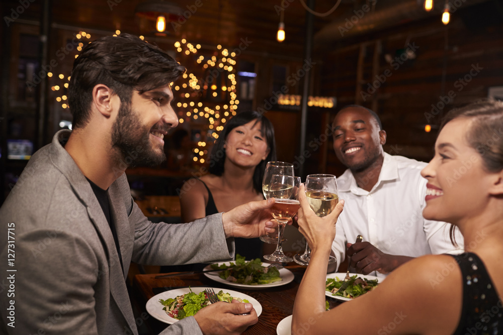 Four friends making a toast over dinner at a restaurant Stock Photo ...
