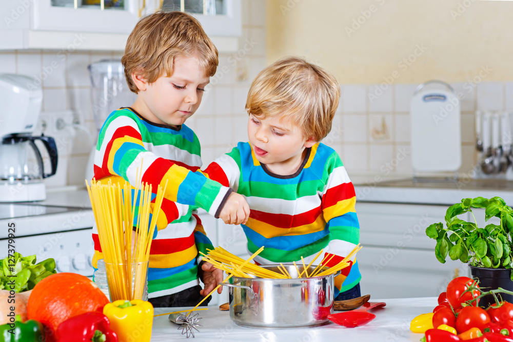 Two little kid boys cooking pasta with vegetables Stock-Foto | Adobe Stock