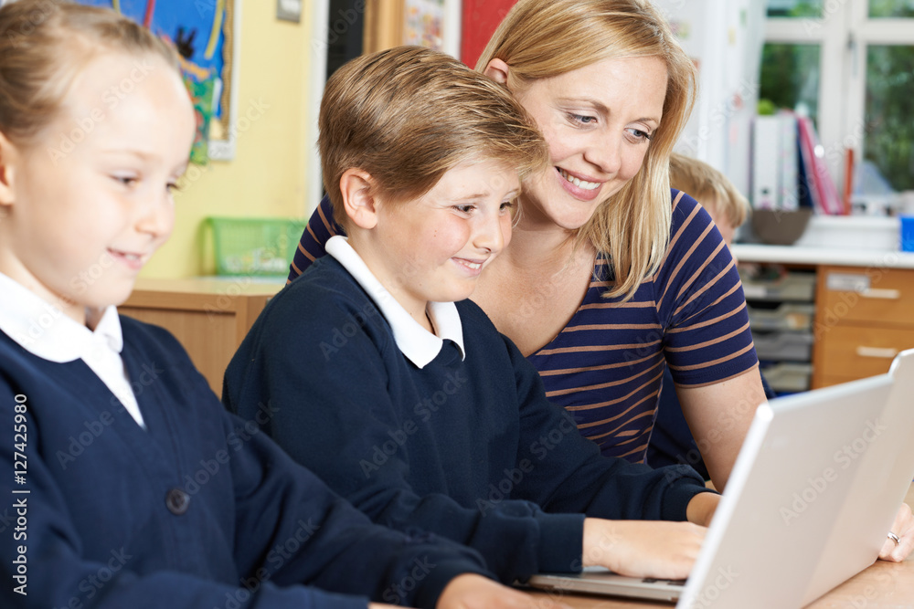 Teacher Helping Elementary School Pupils In Computer Class Stock Photo ...