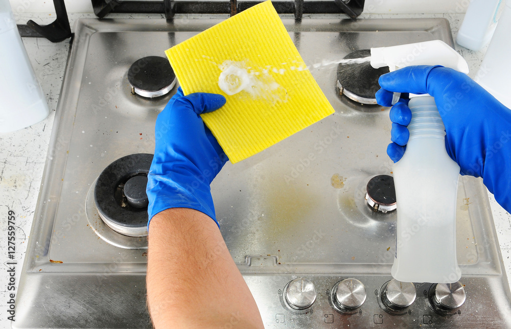 Foto de Cleaner sprinkles detergent on a cloth for cleaning the kitchen ...