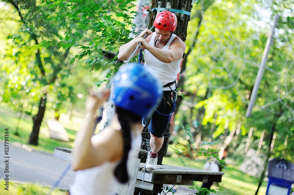 boy and girl climbing on rope road in a special outfit and helmet. The ...