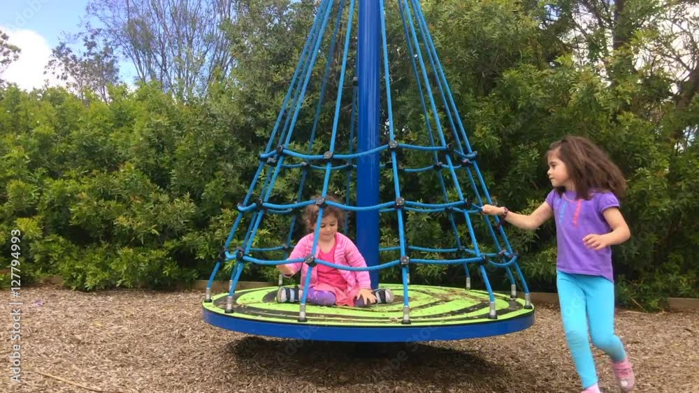 Young girls play on a carousel in the playground. Childhood concept ...