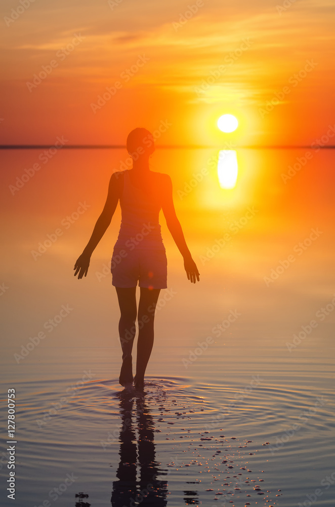 Beautiful female model open arms under sunrise at seaside. Calm water ...