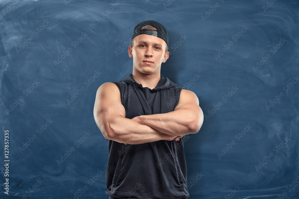 Muscular young man in sportswear standing with his arms folded on the ...