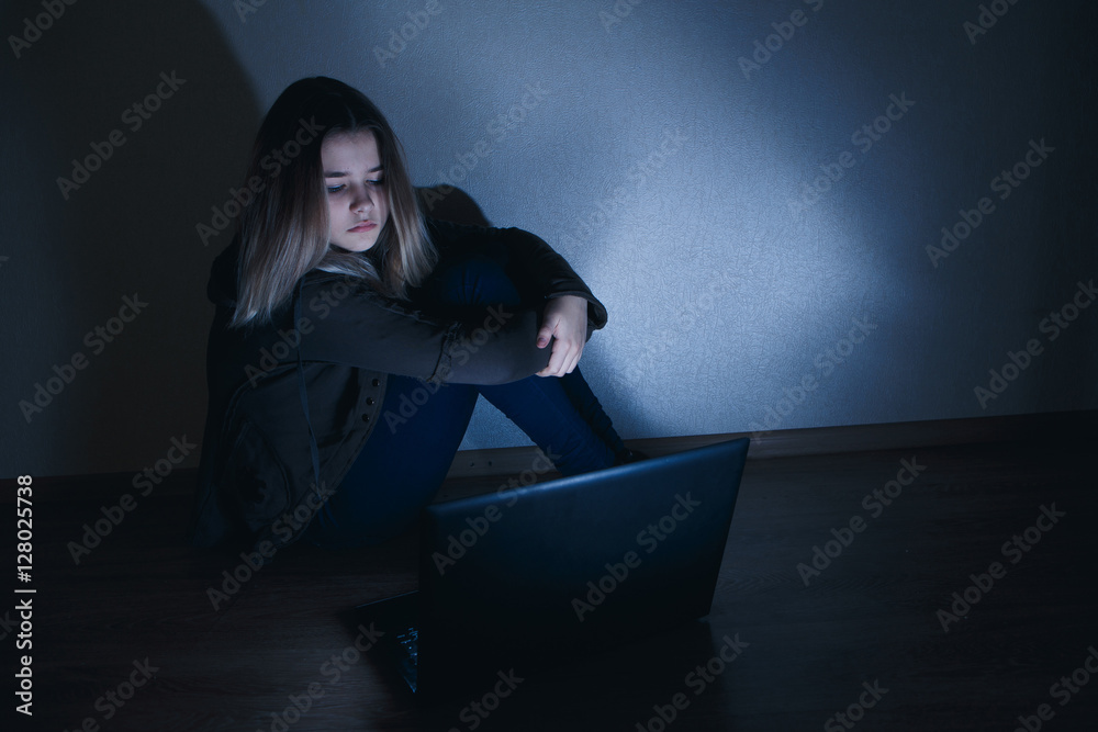 sad and scared female teenager with computer laptop suffering ...