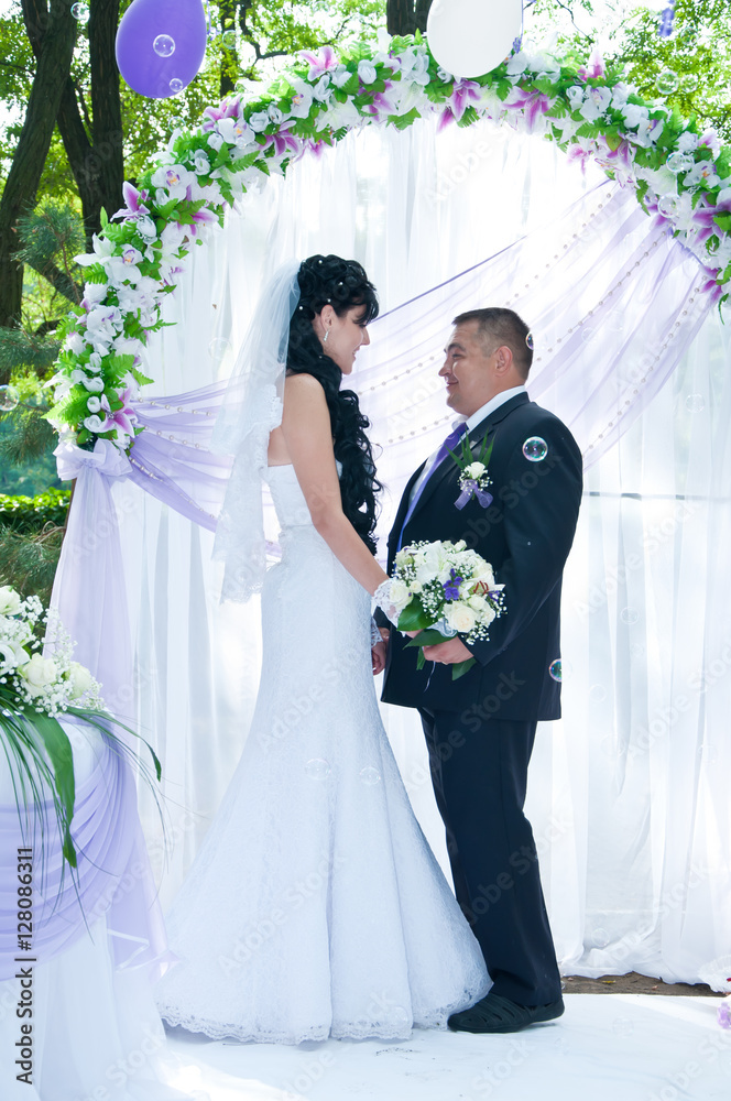 The bride and groom under the wedding arch swear in love and ...