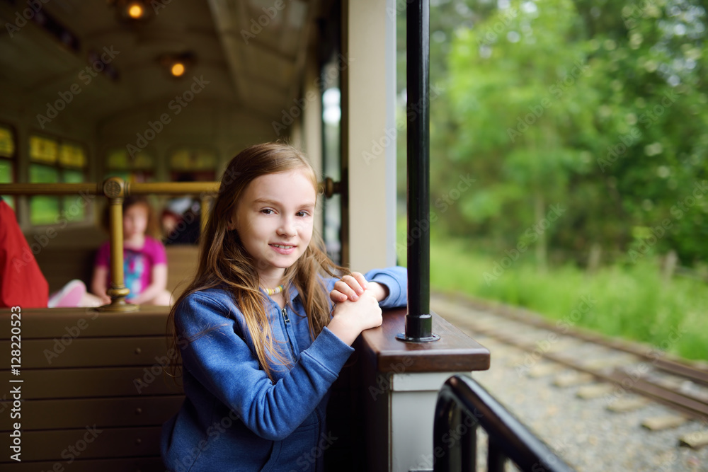 Happy little girl riding a train in a theme park or funfair Stock Photo ...