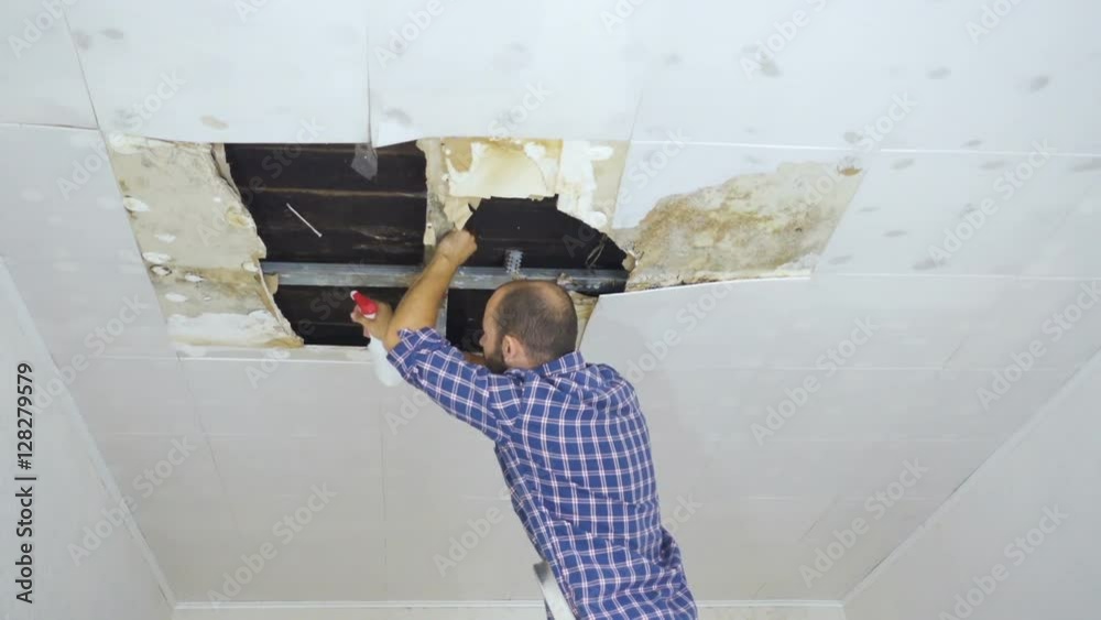 man cleaning mold on ceiling.Ceiling panels damaged huge hole in roof ...