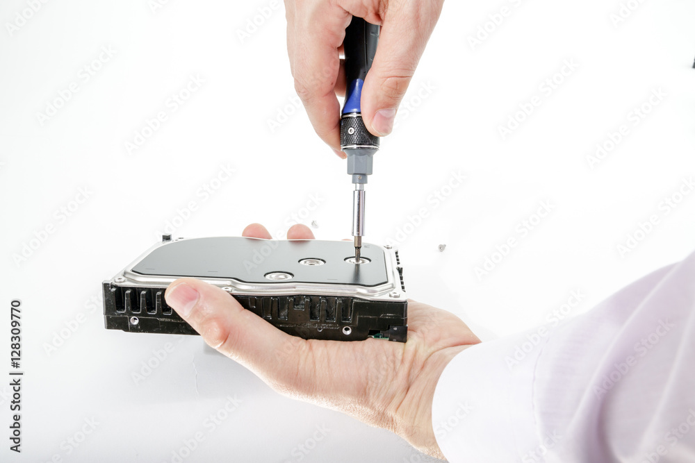 Man's hand holds 3.5 HDD. His another hand unscrews the hard drive case ...
