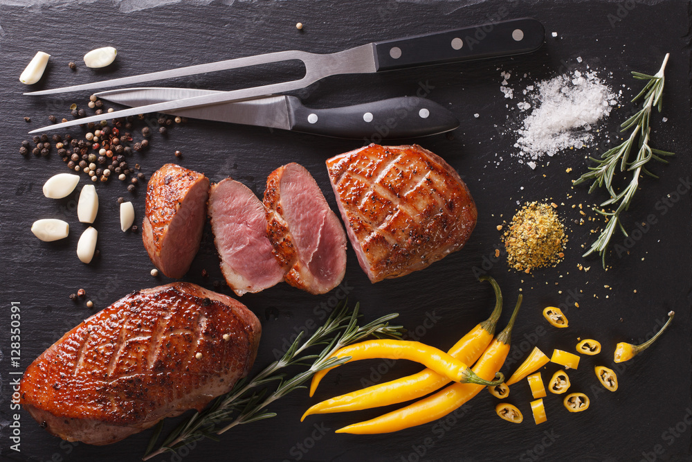 Roast duck fillet with herbs and spices close-up on a slate board ...