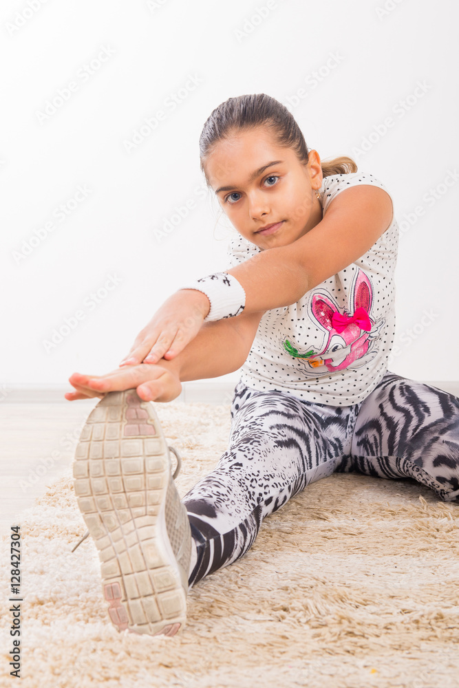 Beautiful teenage girl doing stretching exercises, girl on the carpet ...