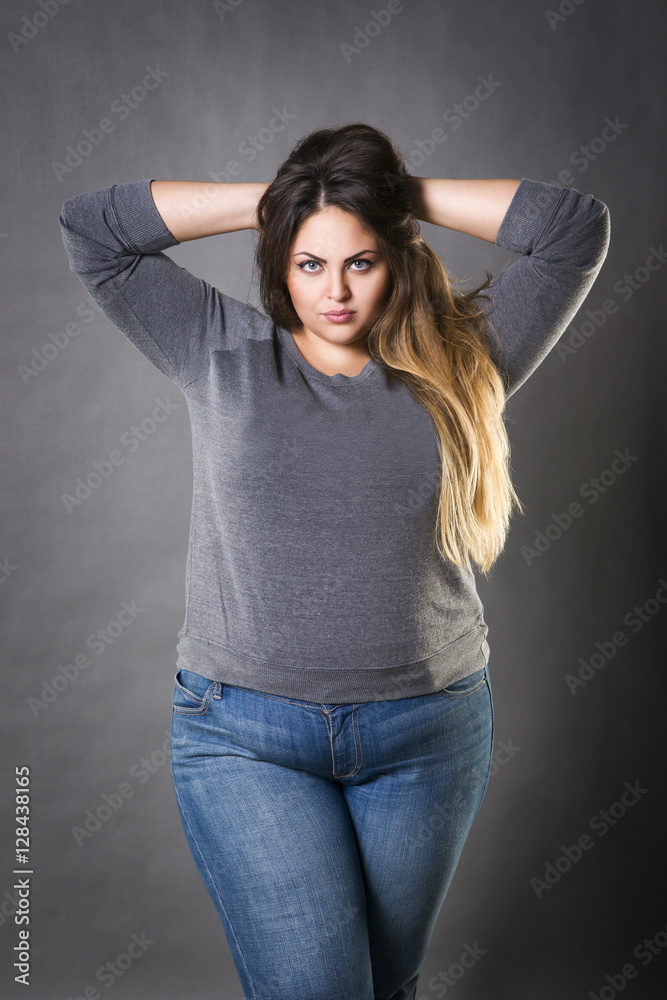 Young beautiful plus size model in blue jeans, xxl woman on gray ...