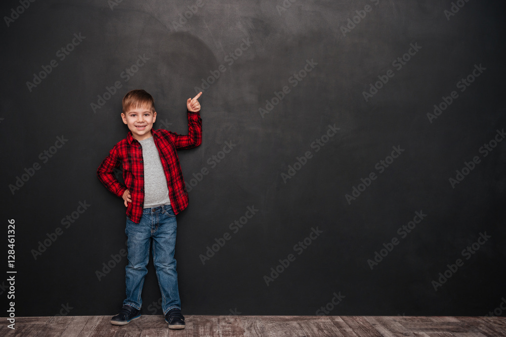 Cute little boy standing over chalkboard and pointing up Stock Photo ...