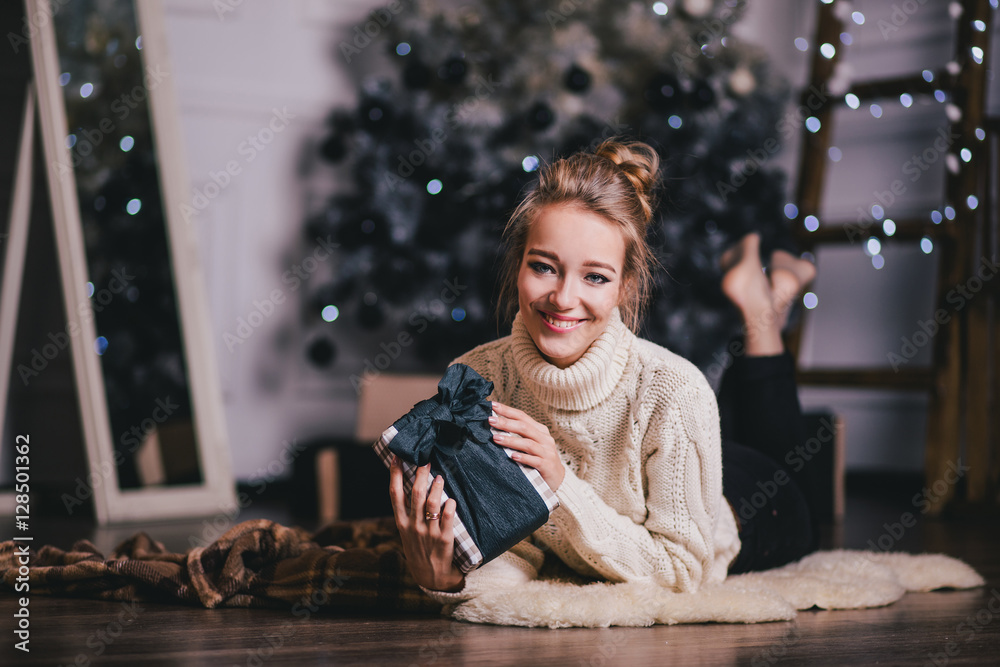 Beautiful young woman posing under Christmas tree in a holiday interior ...