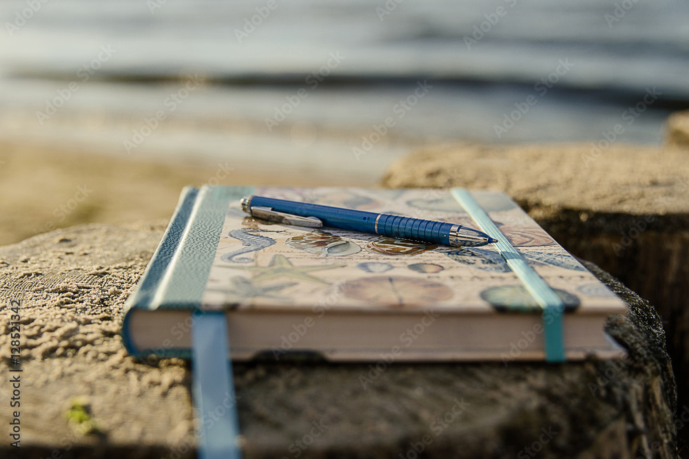 Notizbuch mit Stift am Strand Stock-Foto | Adobe Stock