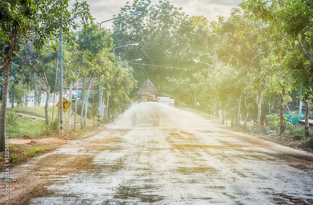 A water truck sprays water on a fresh fill layer of soil and rock for a ...